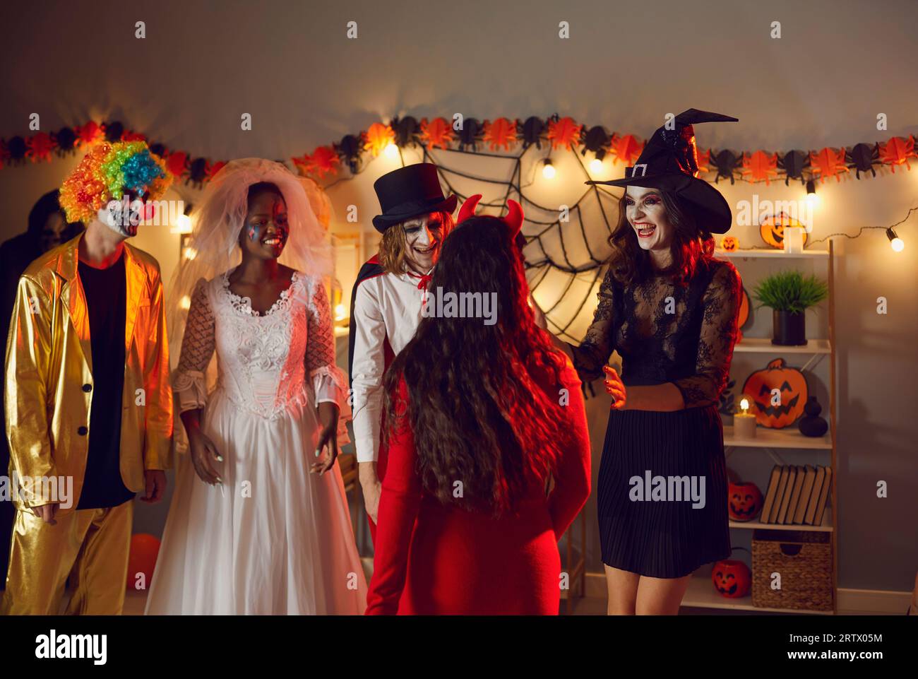 Group of friends in various scary costumes have fun talking to each ...