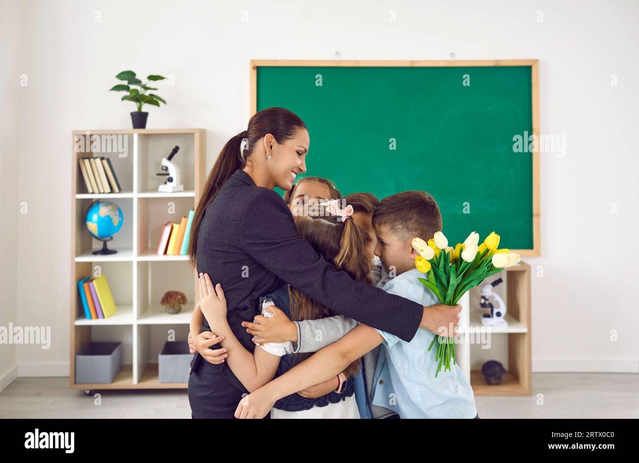 Schoolchildren hugging with teacher holding bouquet of flowers Stock ...