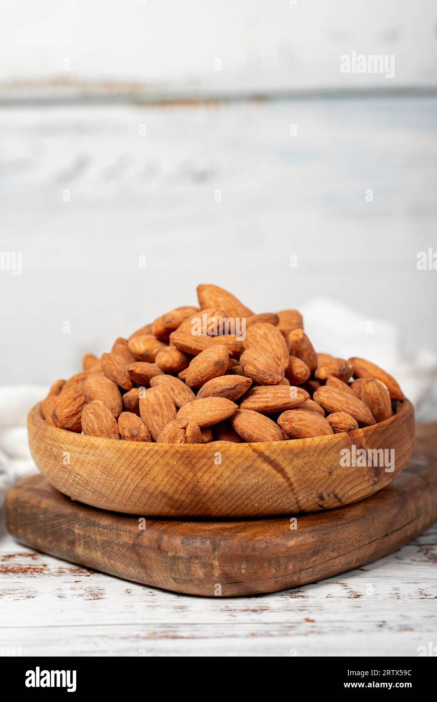 Almond in wood bowl. Roasted almonds on white wood background. Close up ...