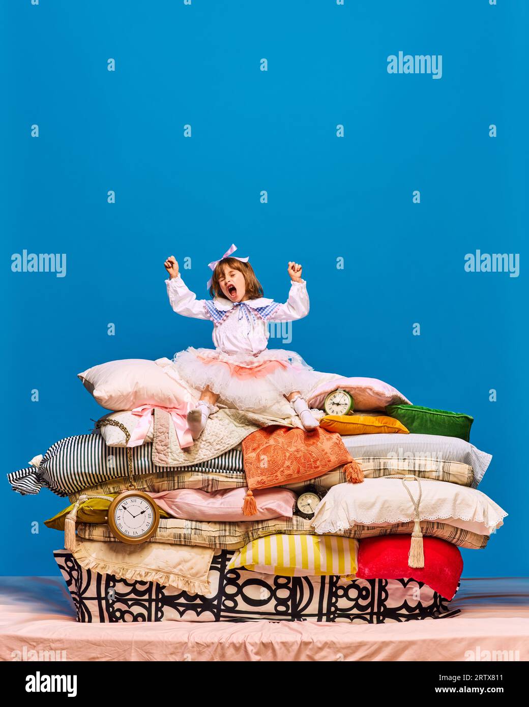 Portrait of sleepy little princess, girl sitting on huge, big pile of ...