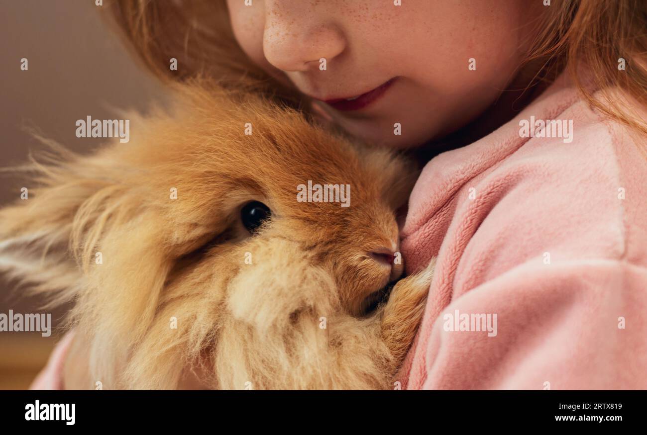 Beautiful young smiling girl is hugging a little red rabbit; child and ...