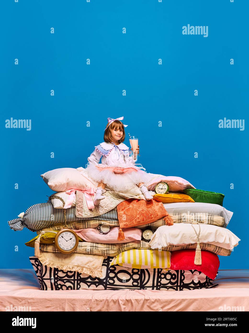 Portrait of smiling, happy little princess sitting on big pile of ...