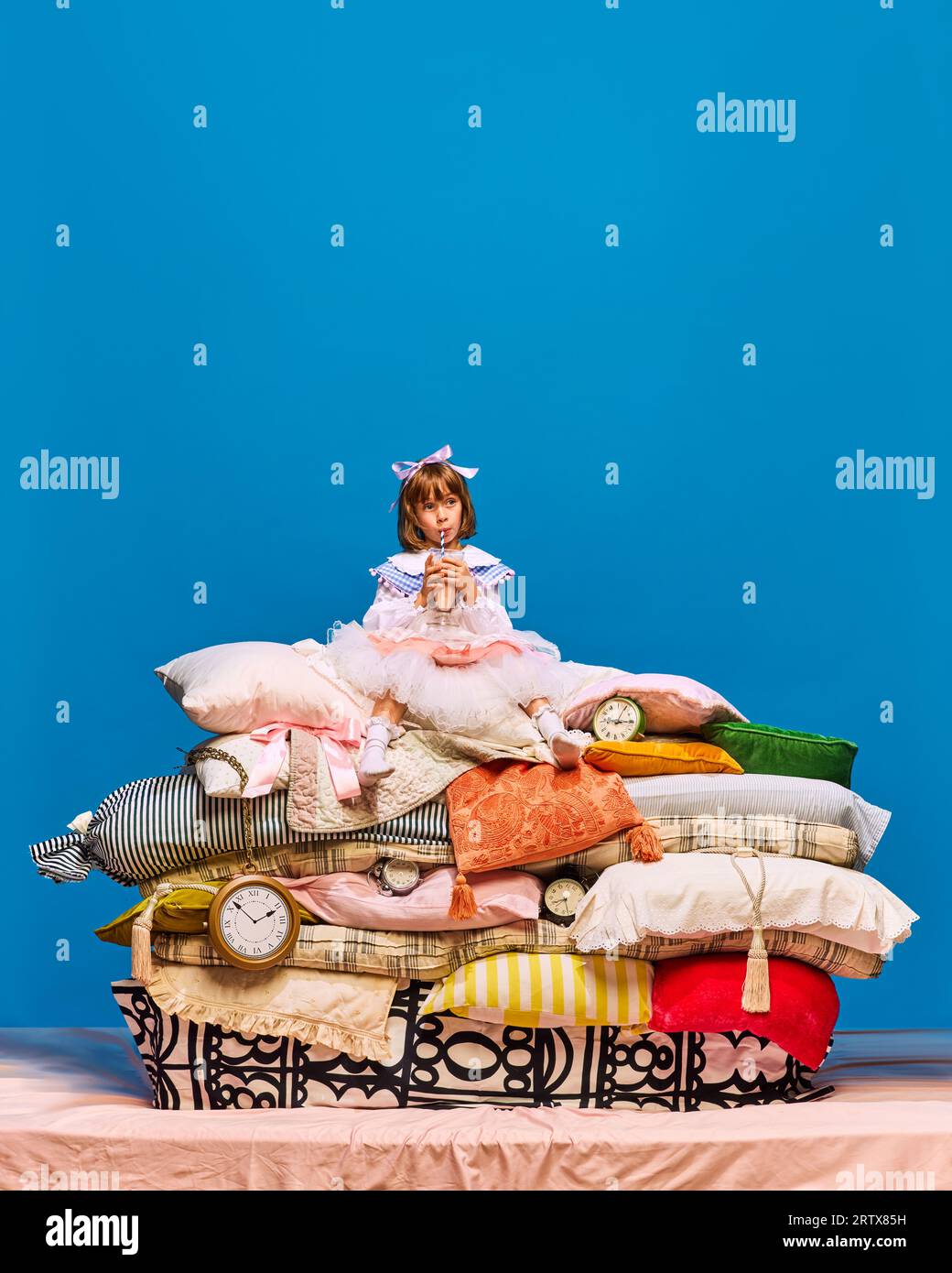 Portrait of smiling, happy little princess sitting on huge, big pile of ...