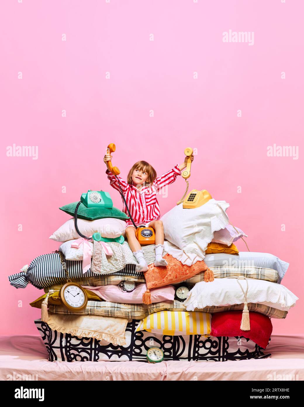 Portrait of pretty little princess sitting on big feather bed with ...