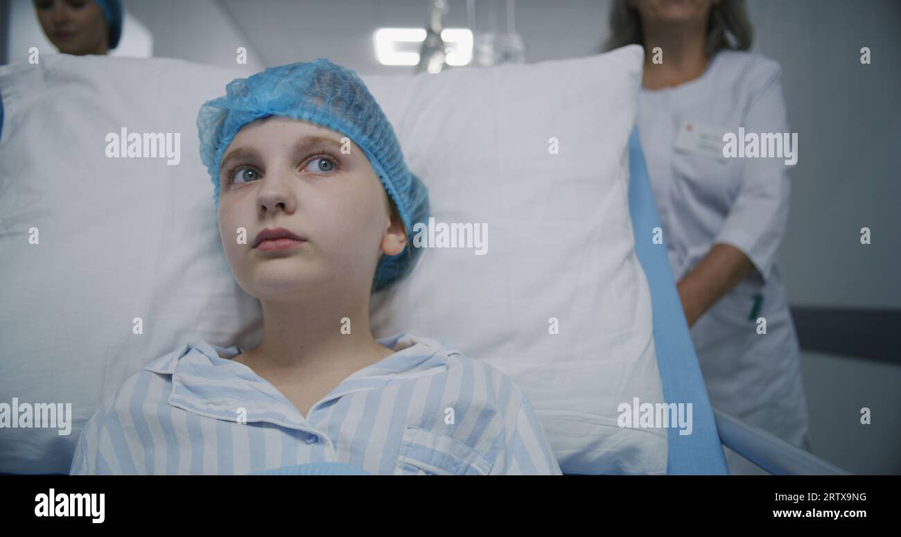 Young girl sits on gurney and looks around. Professional medics walk ...