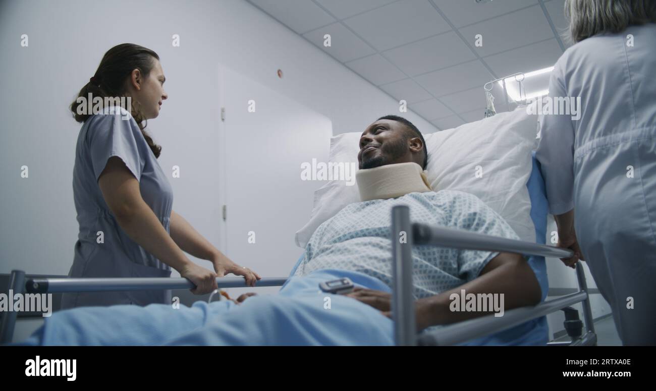 Female medics transport African American patient down clinic corridor ...