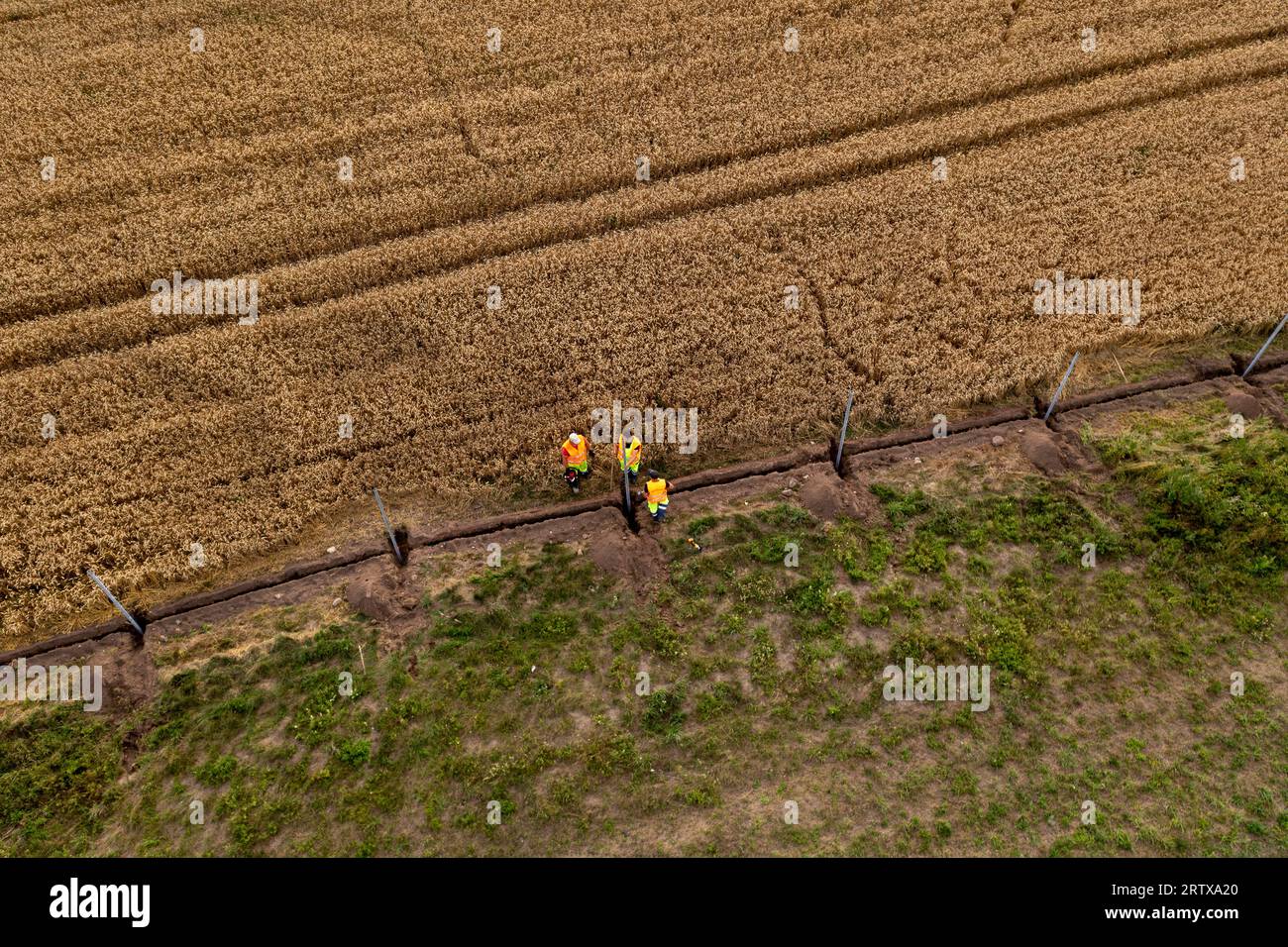 Drone photography of construction workers building a fence between a ...