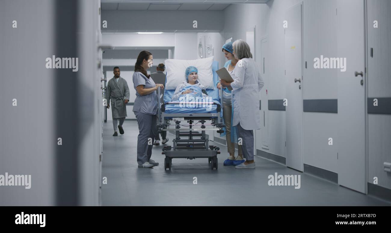 Nurse and mother of child push gurney with young girl in clinic hallway ...