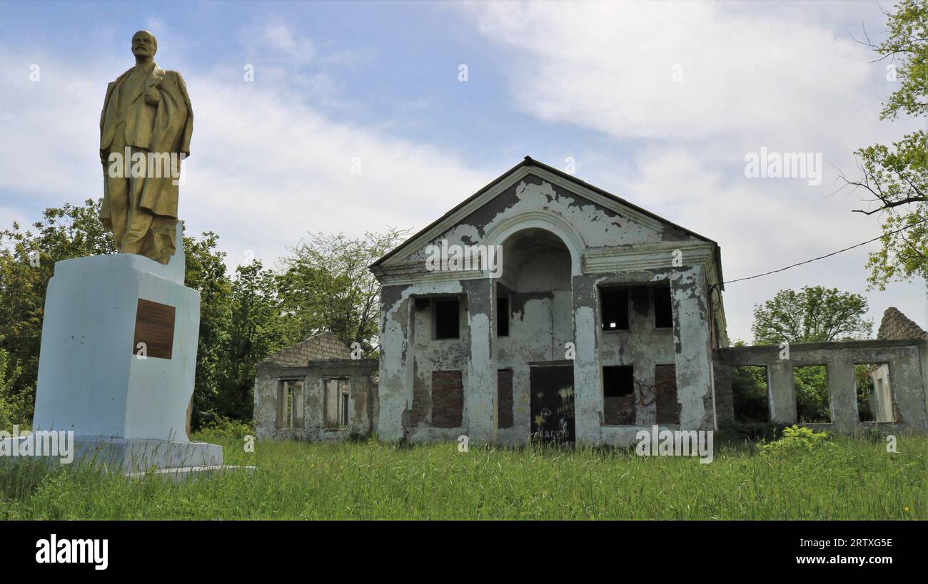 old monument to Vladimir Lenin next to a destroyed abandoned building ...