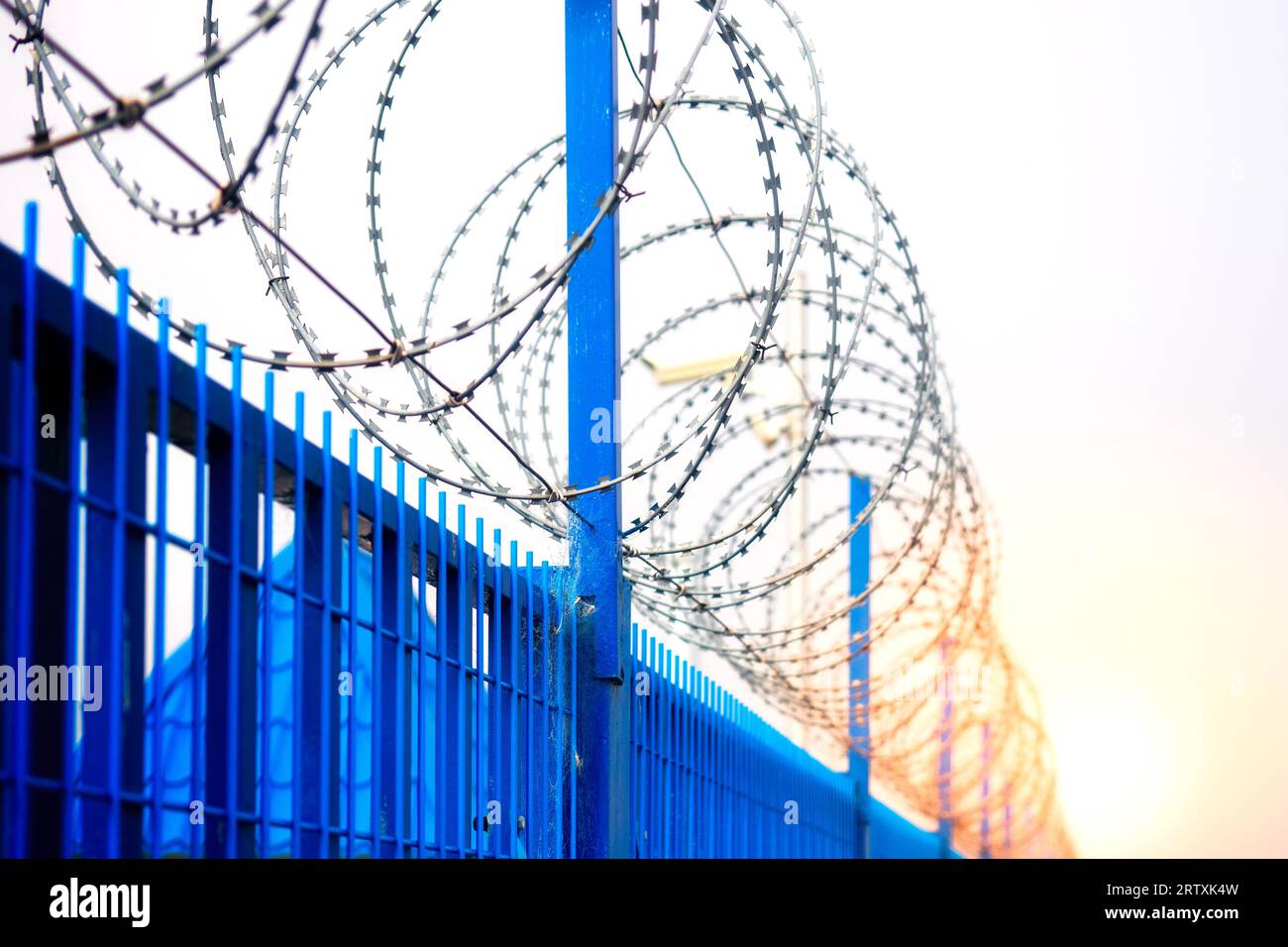 Blue metal fence with barbed wire on top. Fencing around perimeter ...