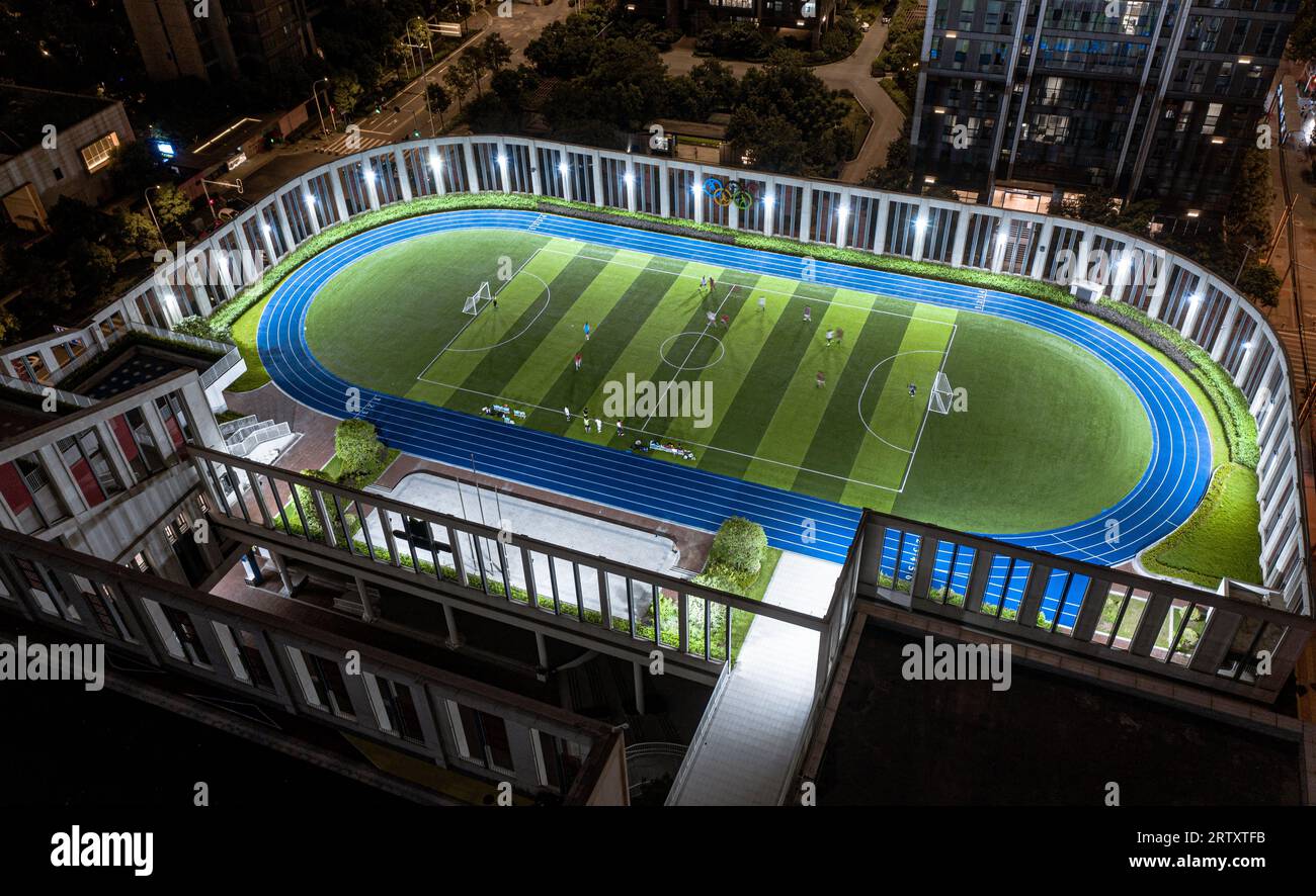 An aerial view of an illuminated soccer field on a tall building roof ...