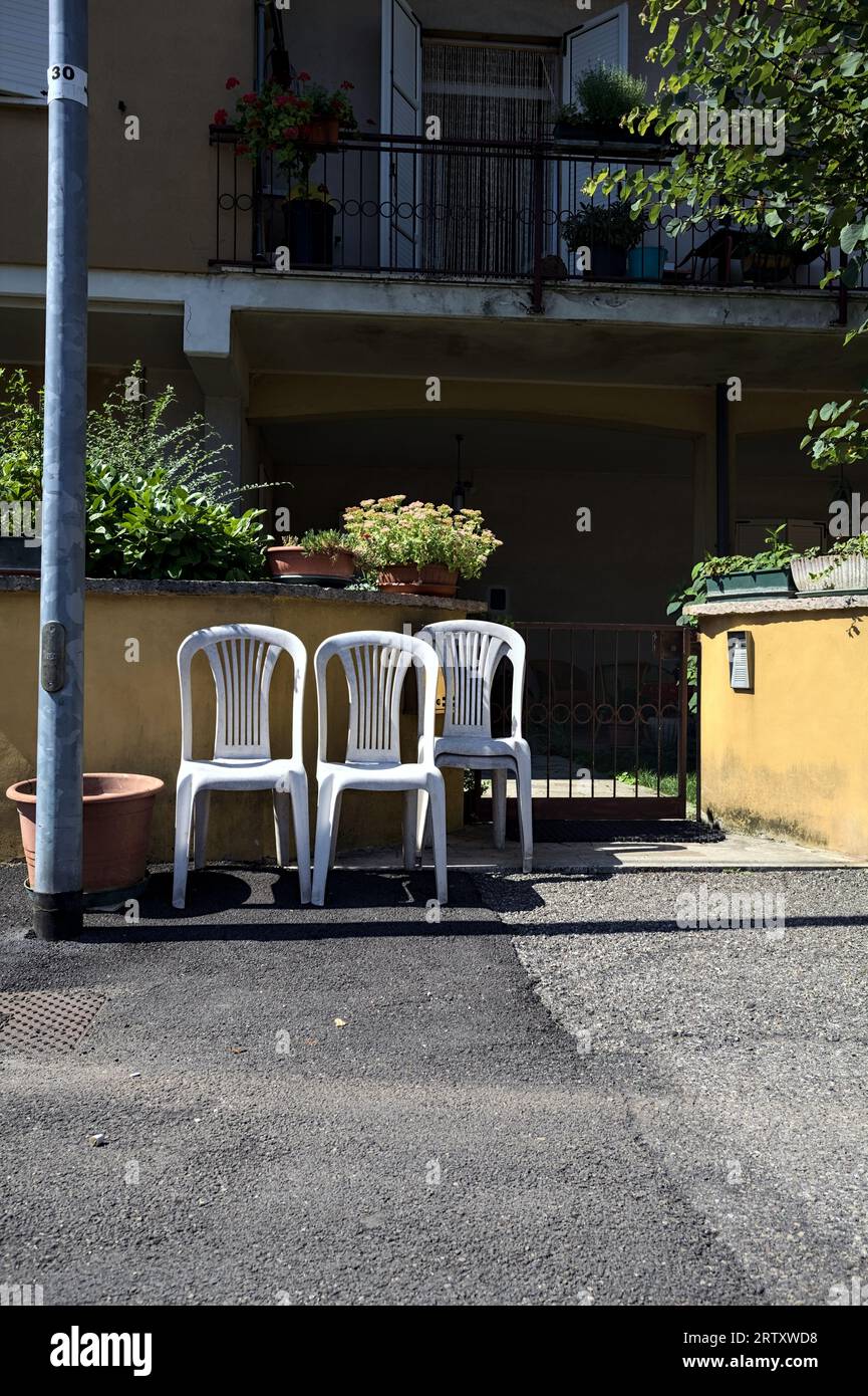 Plastic chairs by the edge of a street next to a boundary wall of a ...
