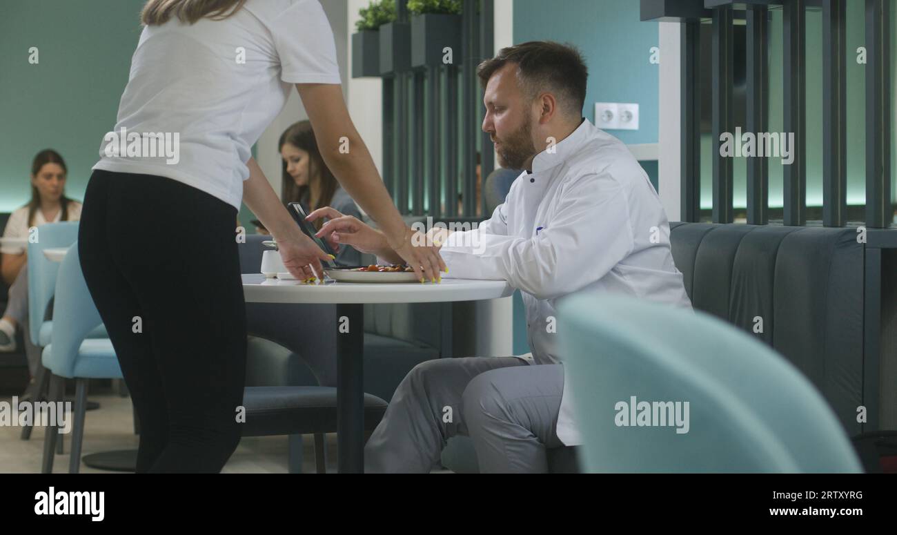 Adult doctor works on digital tablet and eats his dinner in hospital ...
