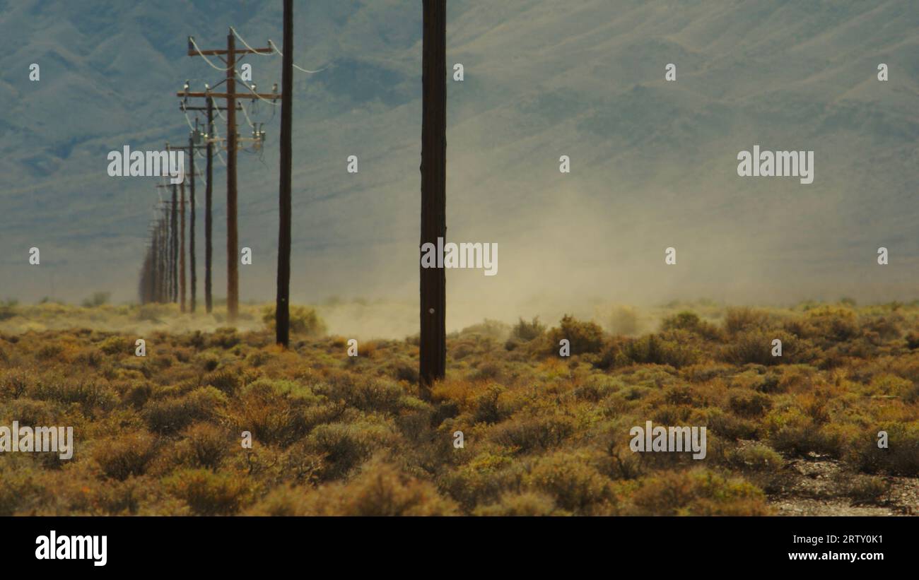 Intense dust devil tears up the desert scrub and roars through a row of ...