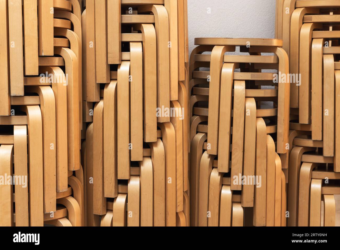 Stacked round wooden stools made from bent plywood stand in front of a ...