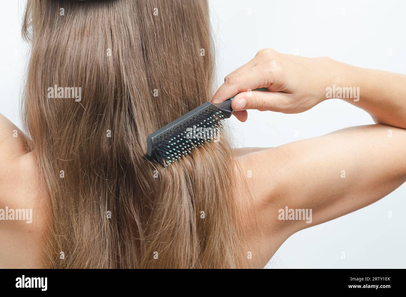 Back view of beautiful woman combing her hair with brush Stock Photo ...
