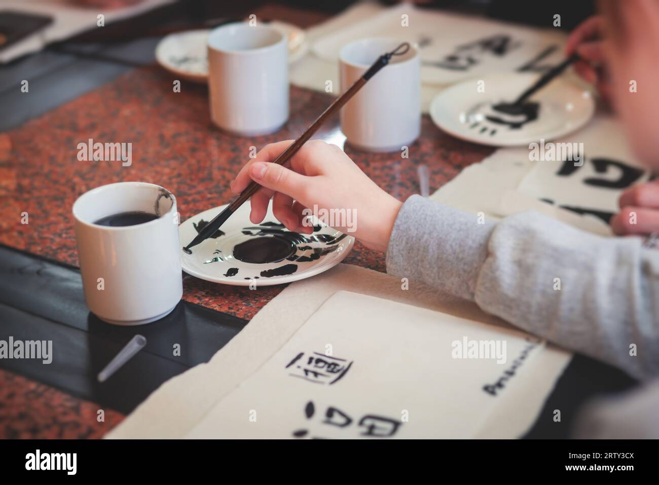 Chinese calligraphy lesson, group of kids learn and practicing traditional calligraphy in class ...