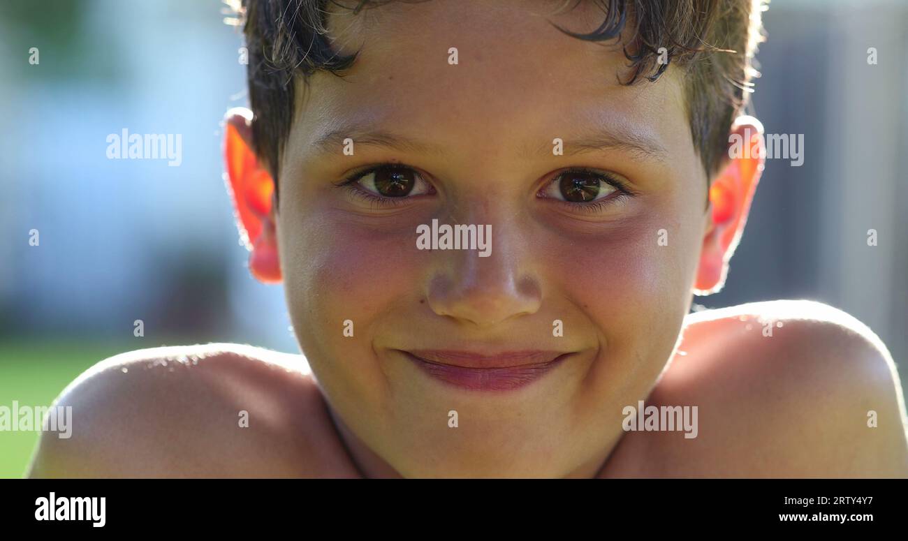 Handsome child boy face portrait smiling to camera outside in sunlight ...