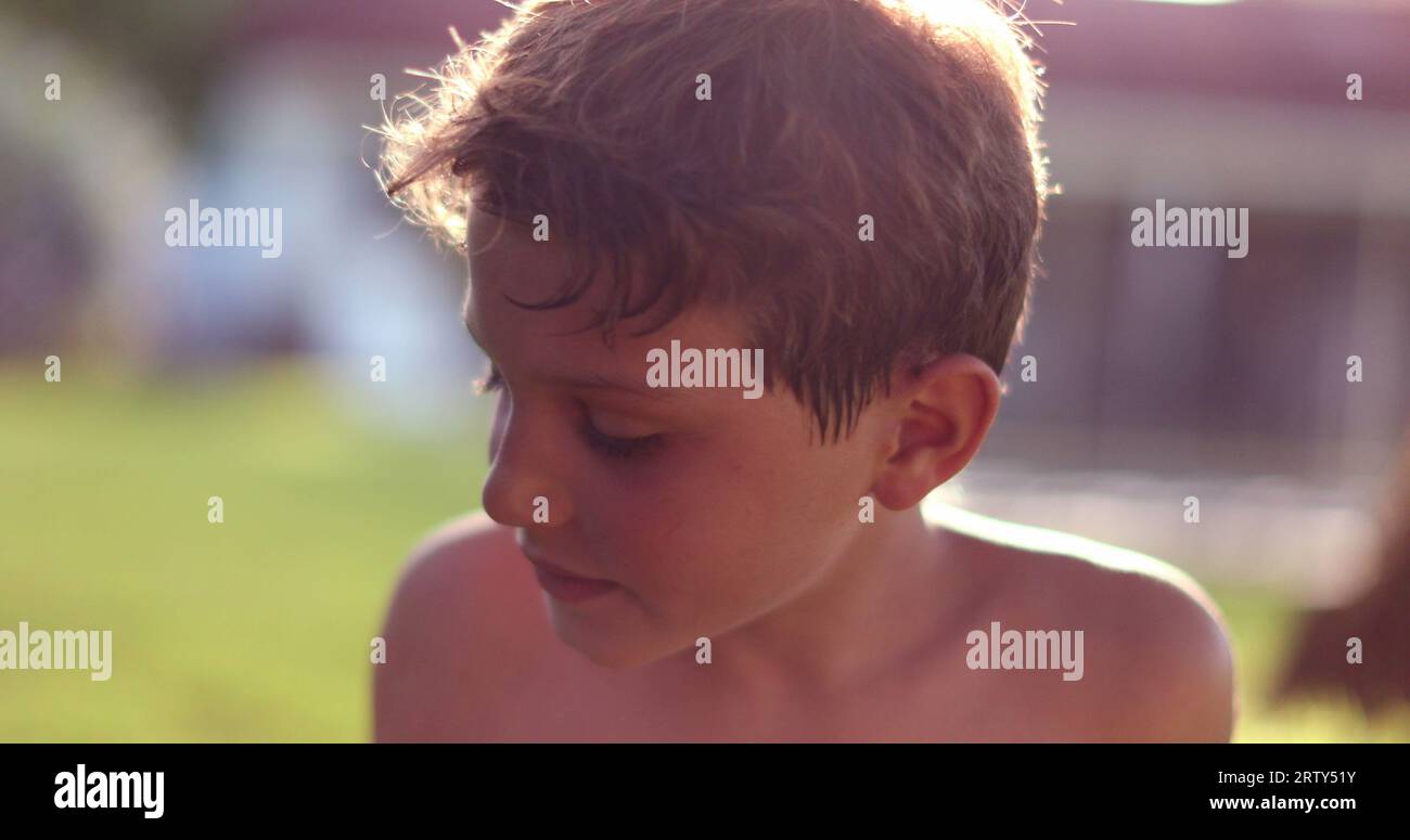 Cute child boy sitting outdoors in sunlight garden portrait face Stock ...