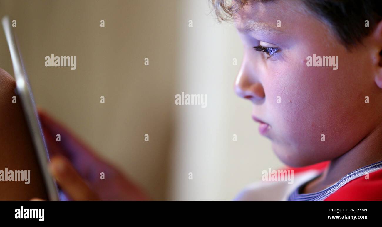 Digital native child addicted to tablet device. Young boy absorbed by ...