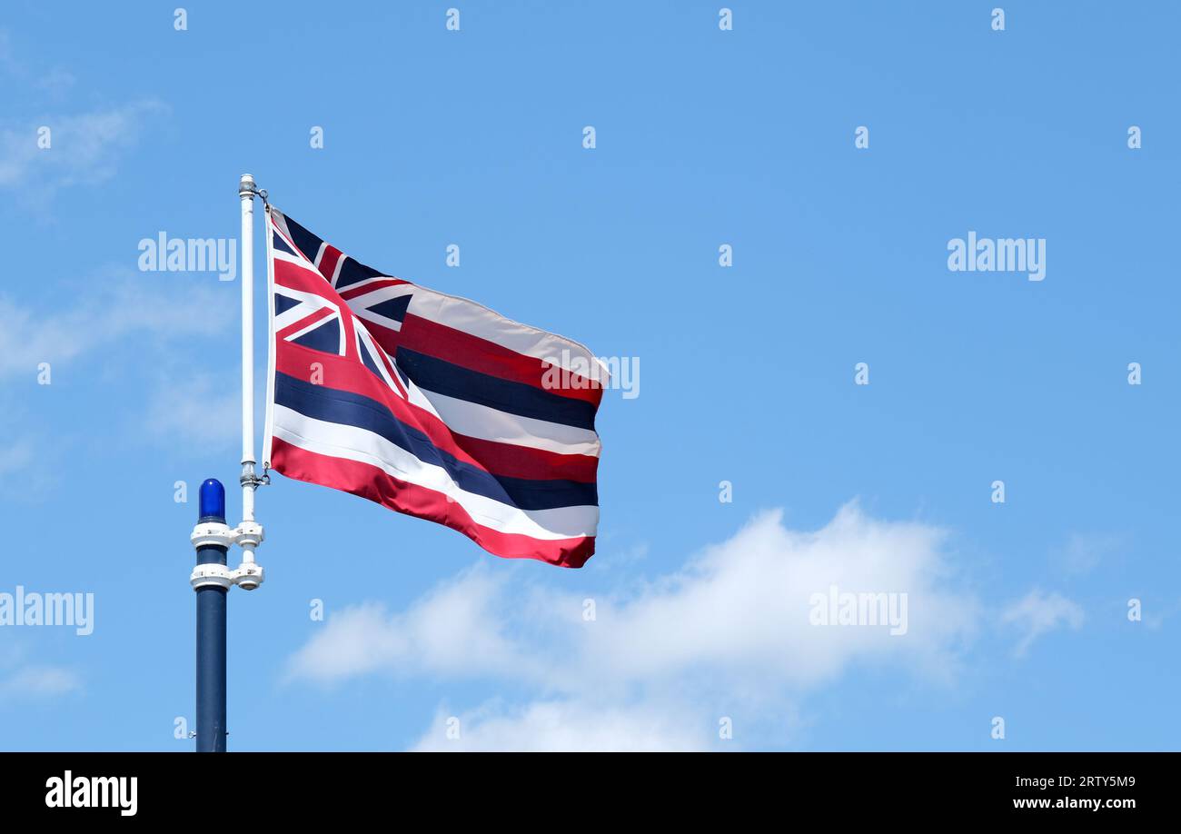 Close up photo of Hawaii state flag against a blue sky background and ...