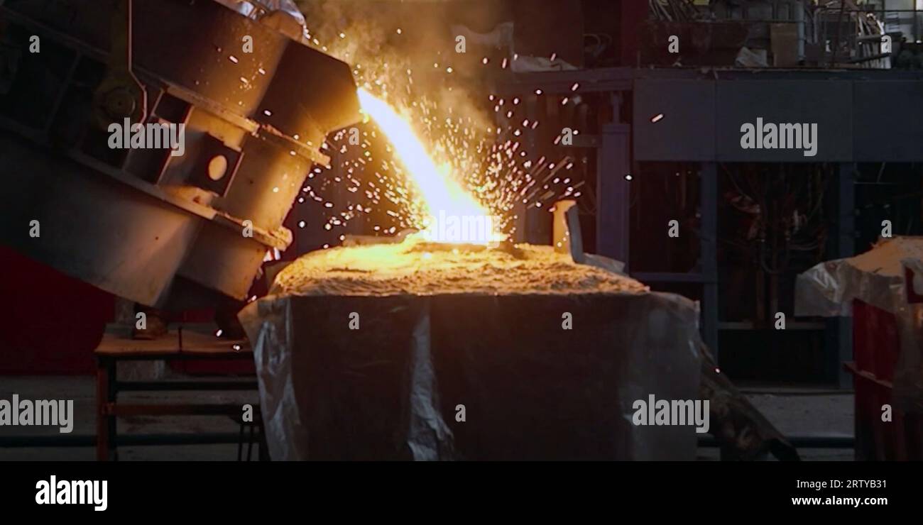Hot molten metal being poured into a mold in a metallurgical plant ...