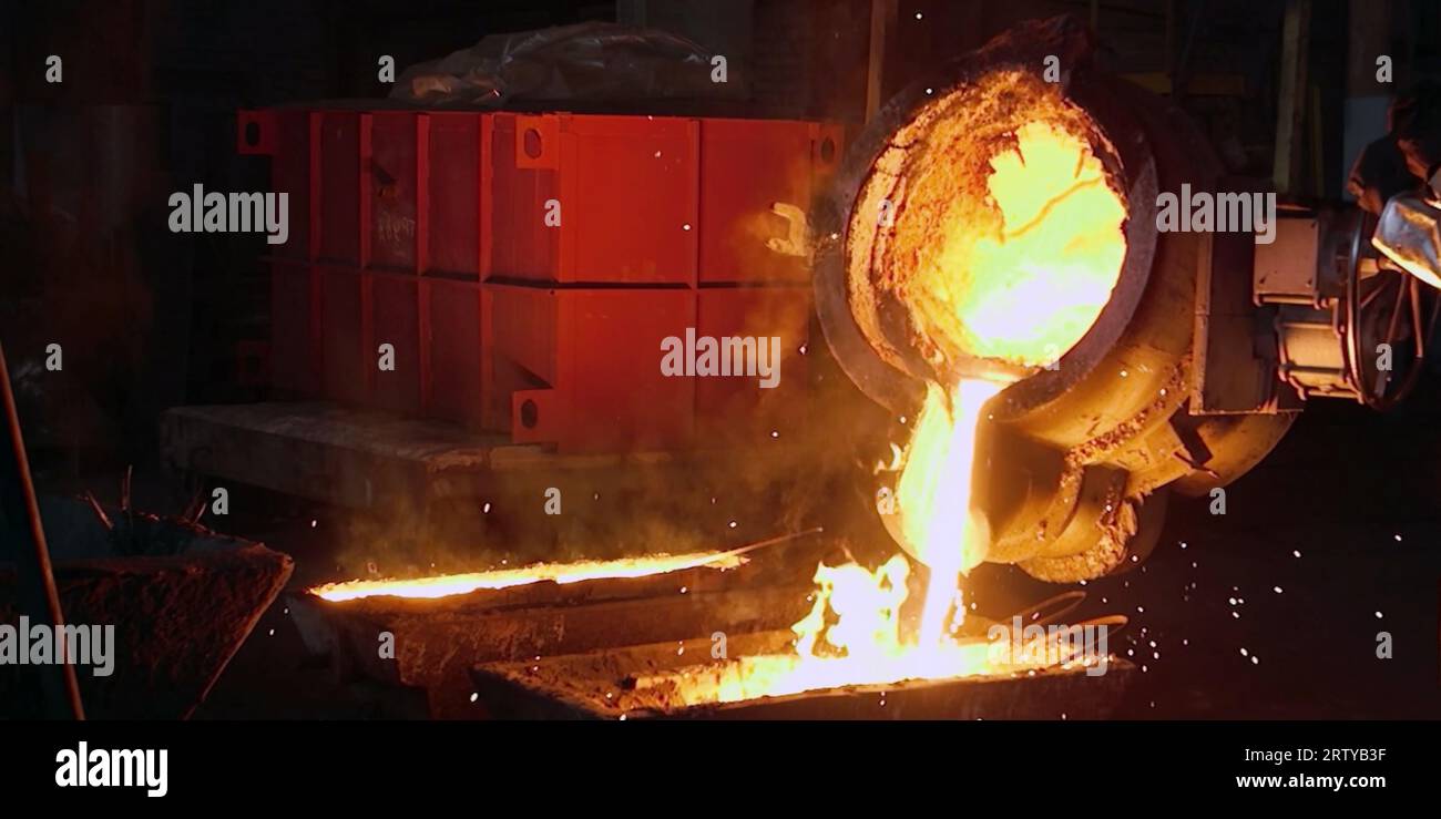 Hot molten metal being poured into a mold in a metallurgical plant ...