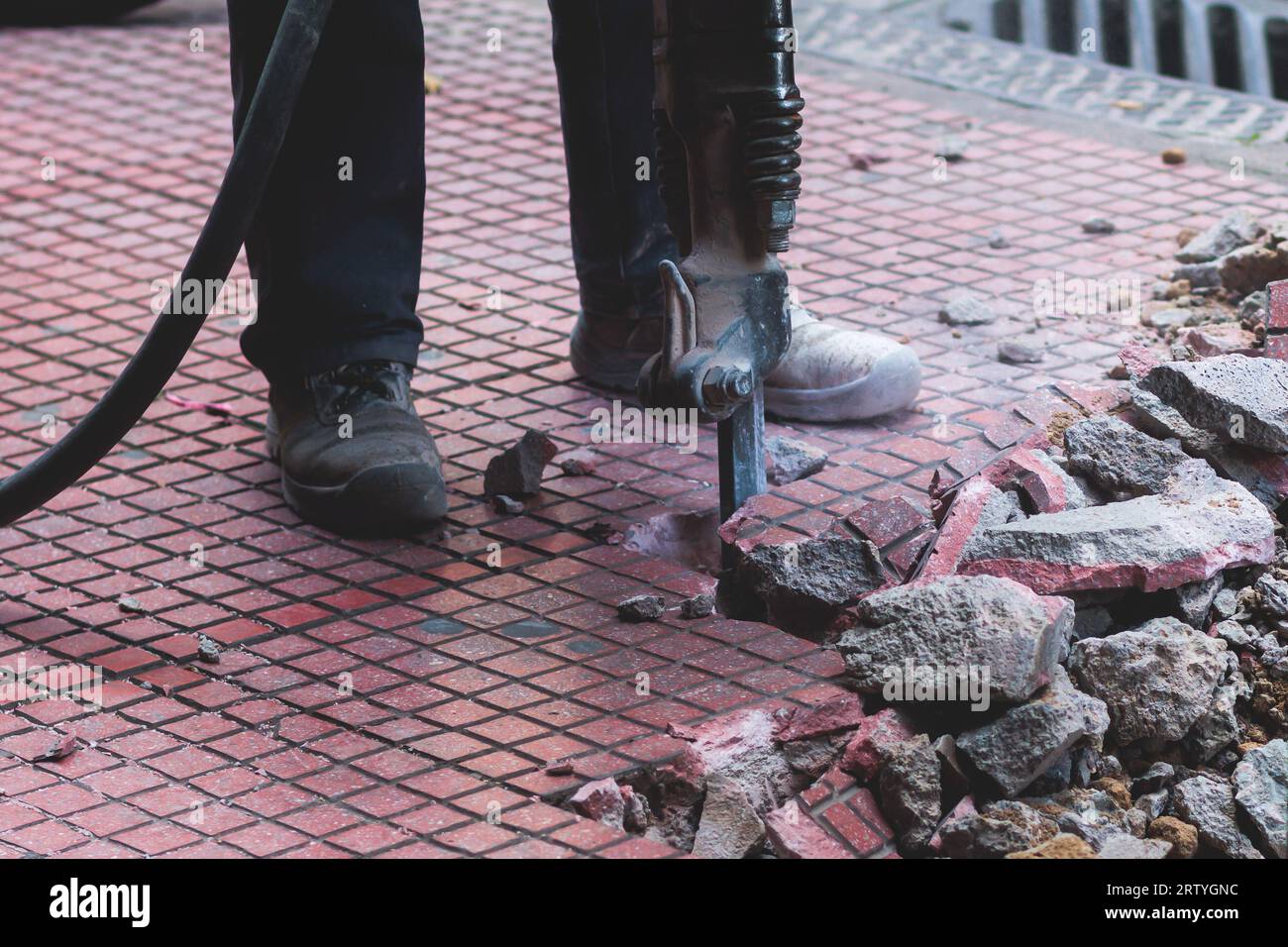 Process of sidewalk road repairing with jackhammer, builder worker with ...