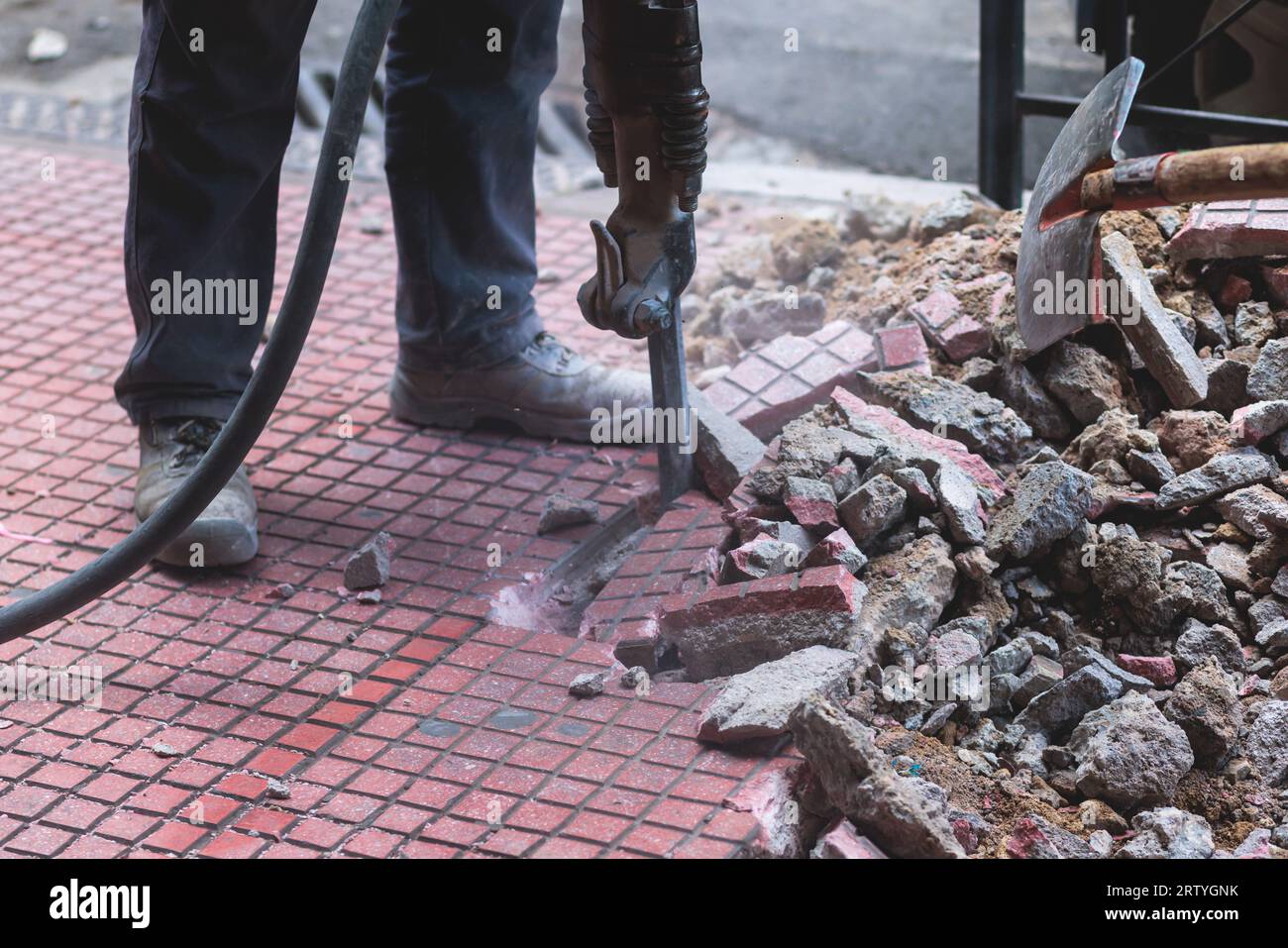 Process of sidewalk road repairing with jackhammer, builder worker with ...