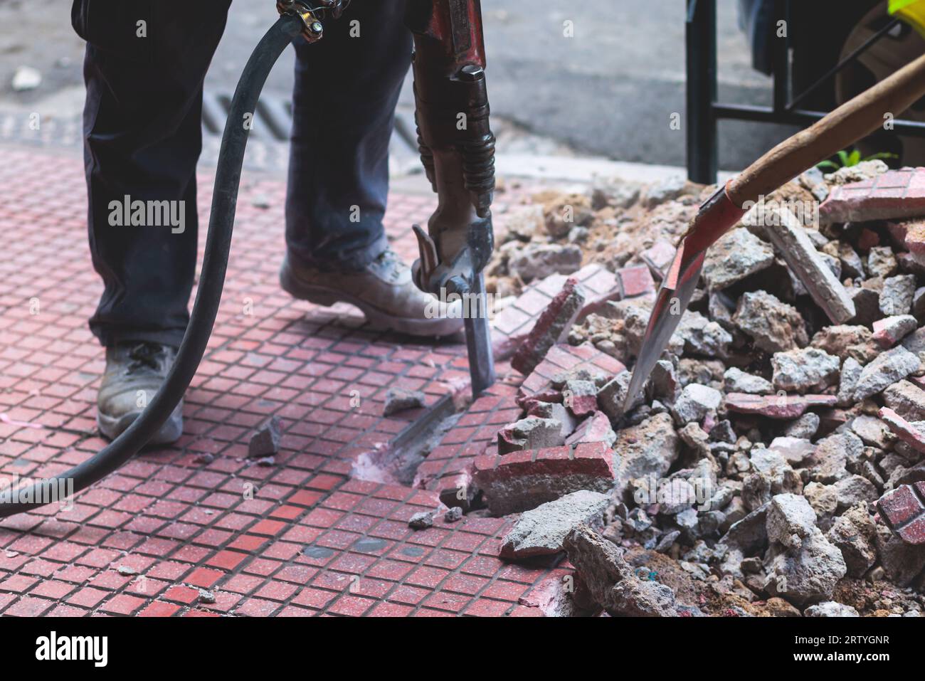Process of sidewalk road repairing with jackhammer, builder worker with ...