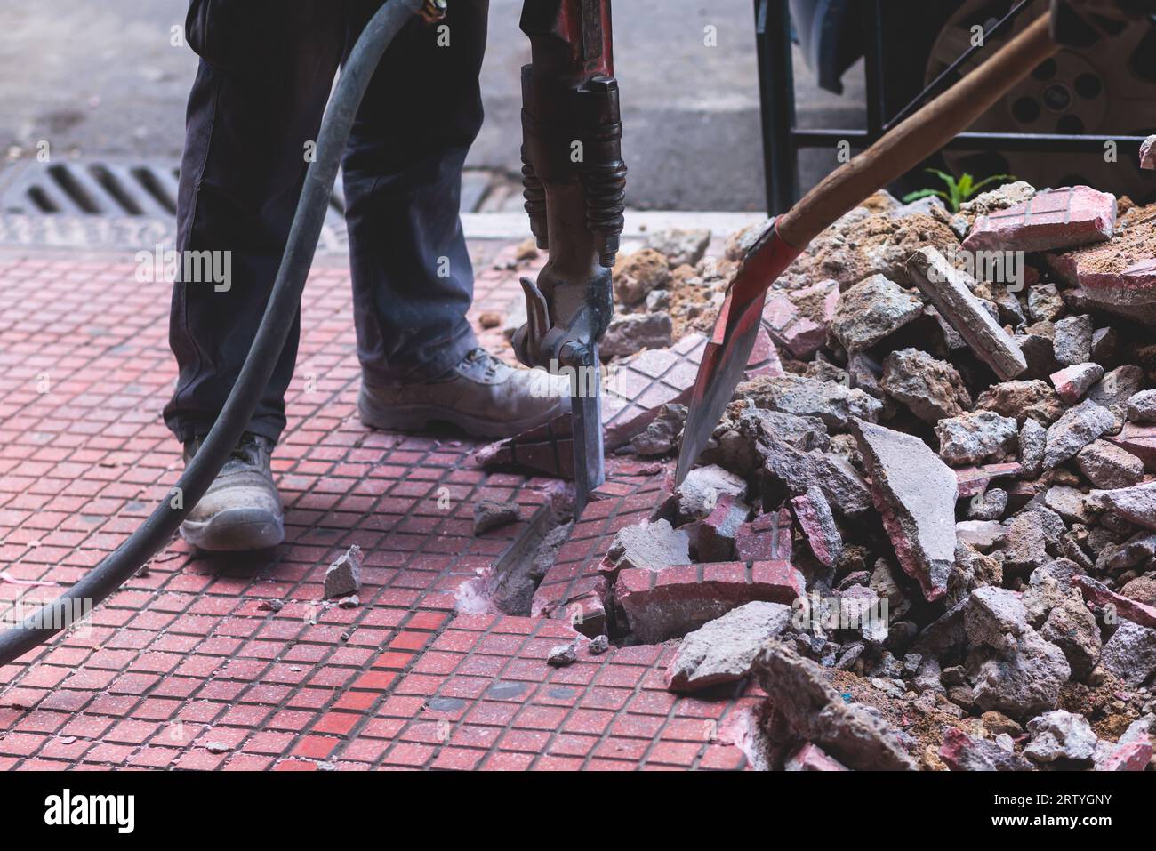 Process of sidewalk road repairing with jackhammer, builder worker with ...