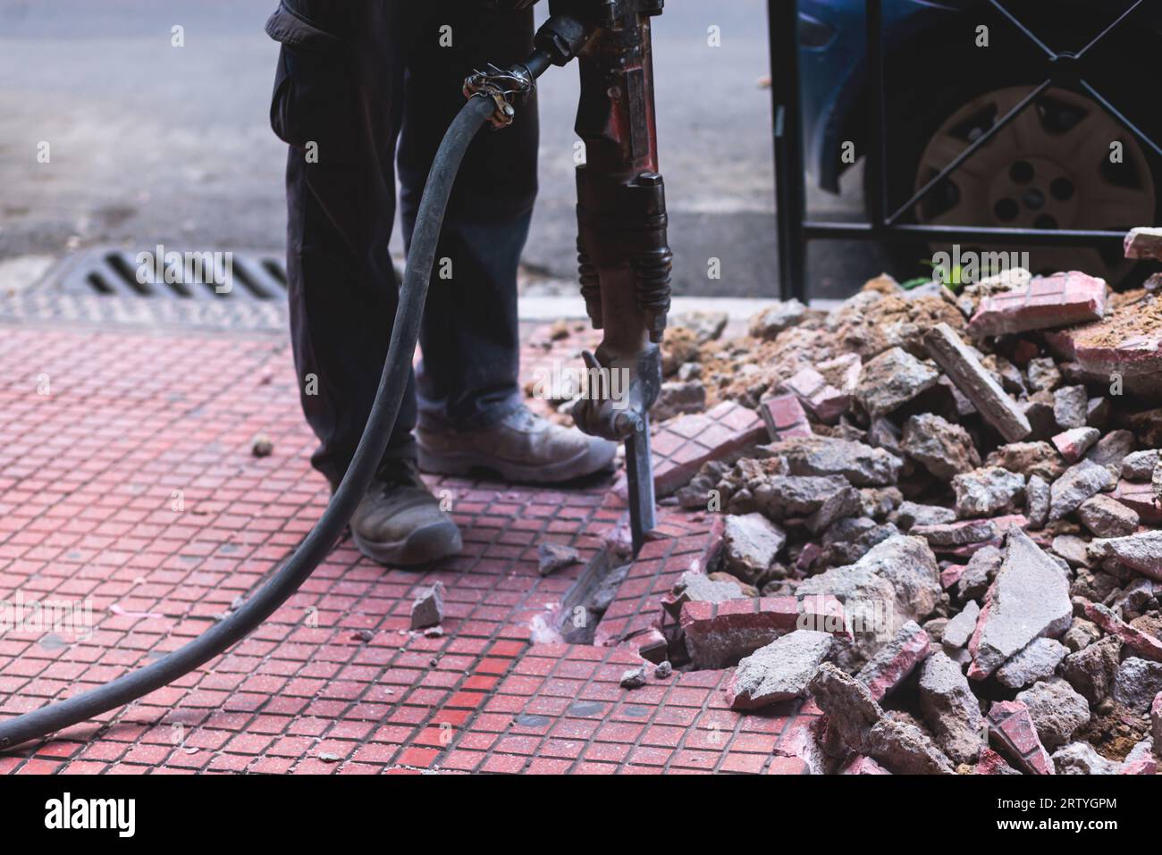 Process of sidewalk road repairing with jackhammer, builder worker with ...