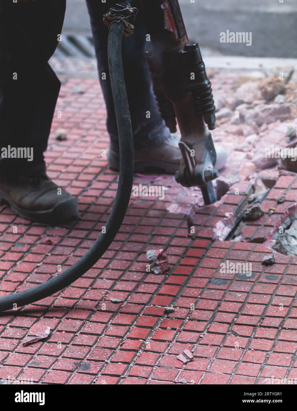 Process of sidewalk road repairing with jackhammer, builder worker with ...