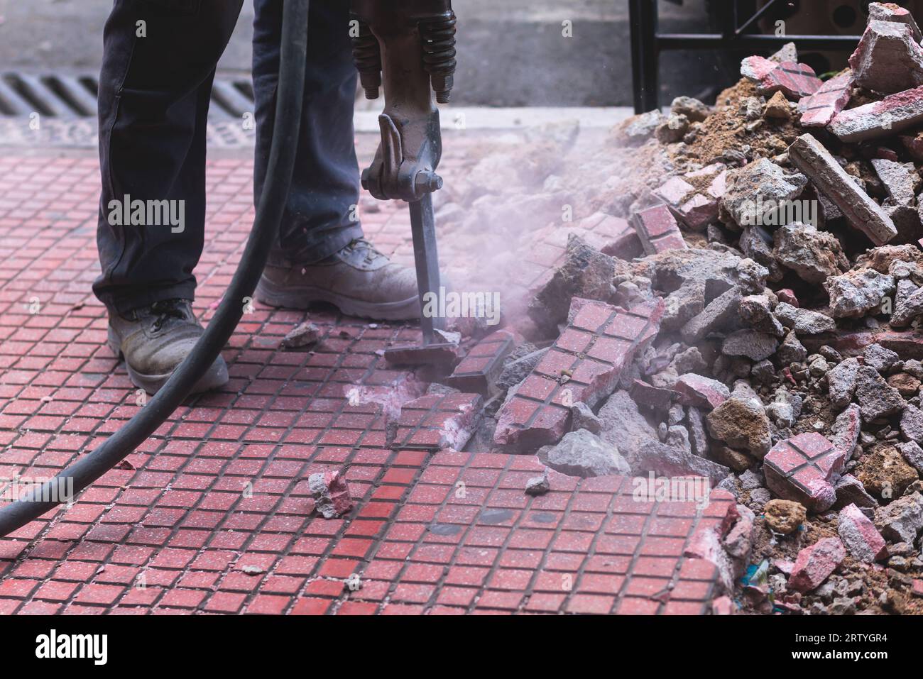Process of sidewalk road repairing with jackhammer, builder worker with ...