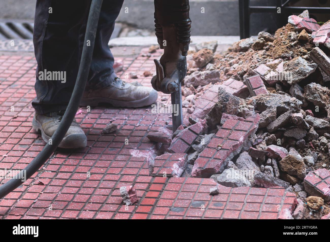 Process of sidewalk road repairing with jackhammer, builder worker with ...