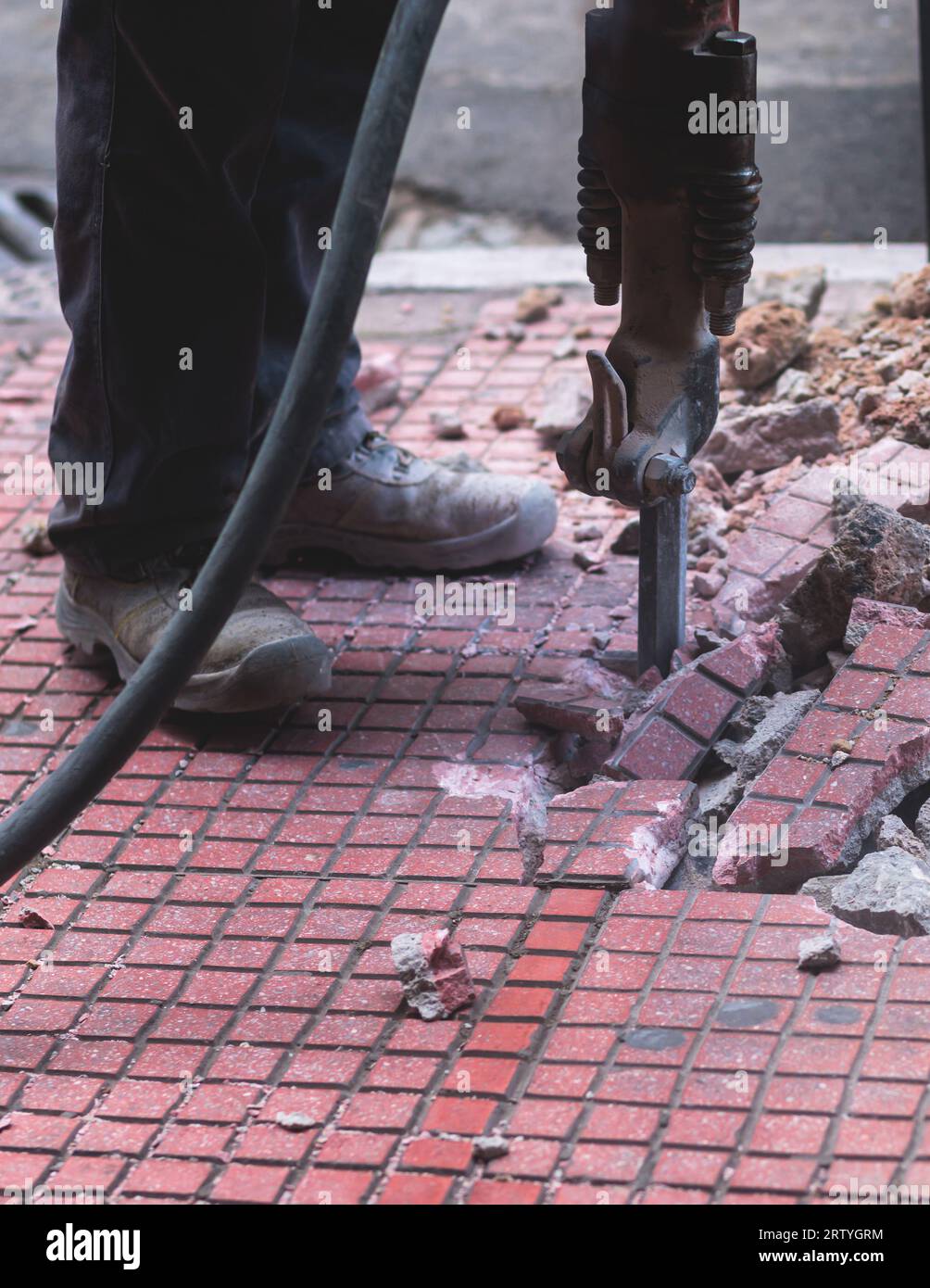 Process of sidewalk road repairing with jackhammer, builder worker with ...
