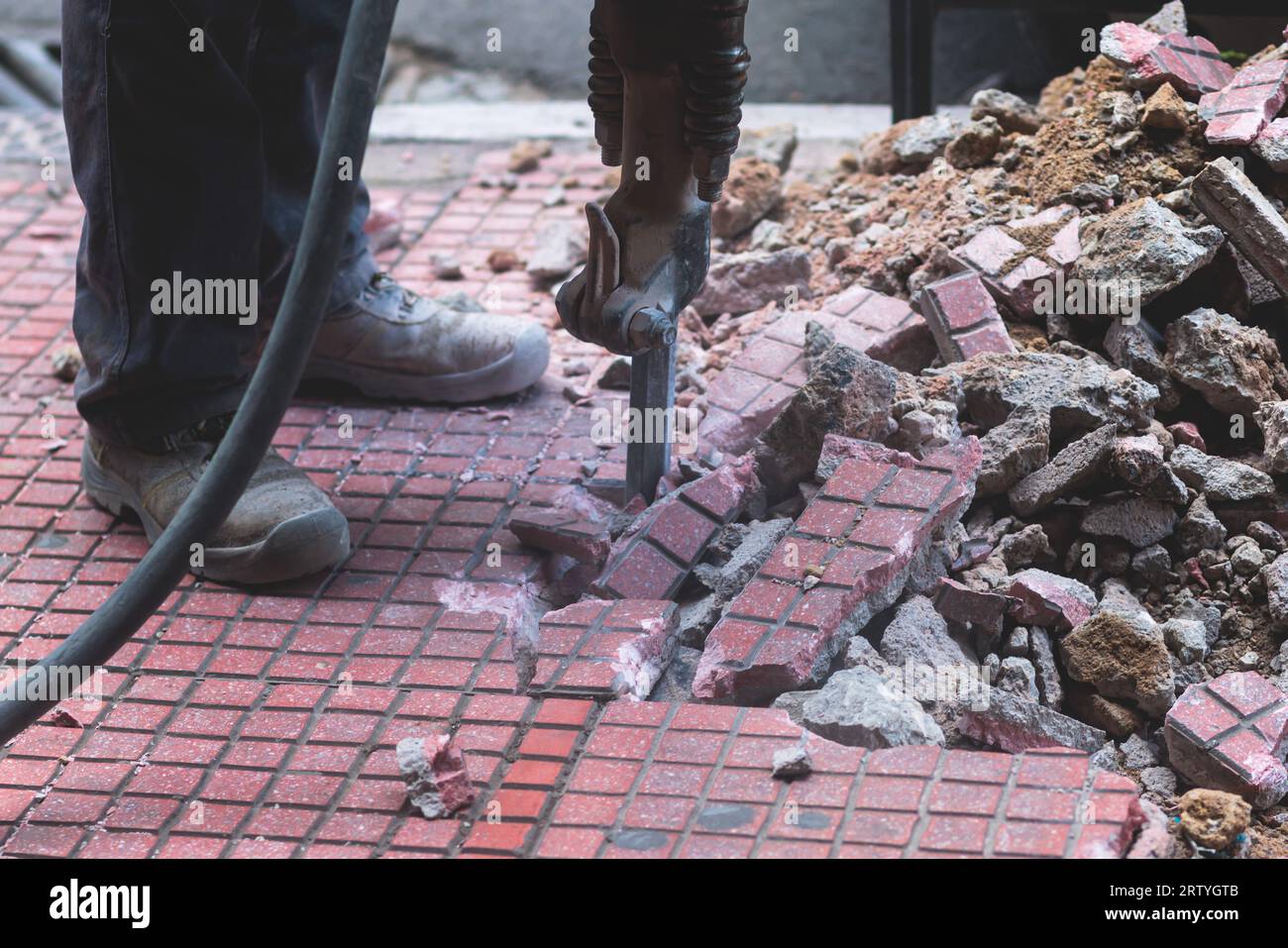 Process of sidewalk road repairing with jackhammer, builder worker with ...