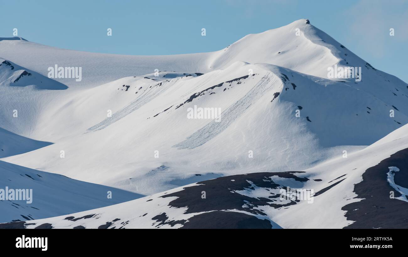 Snow covered mountains with avalanche trails in the arctic in Svalbard ...