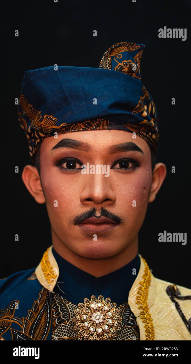 an Asian man wearing a traditional Indonesian dance costume is brown ...