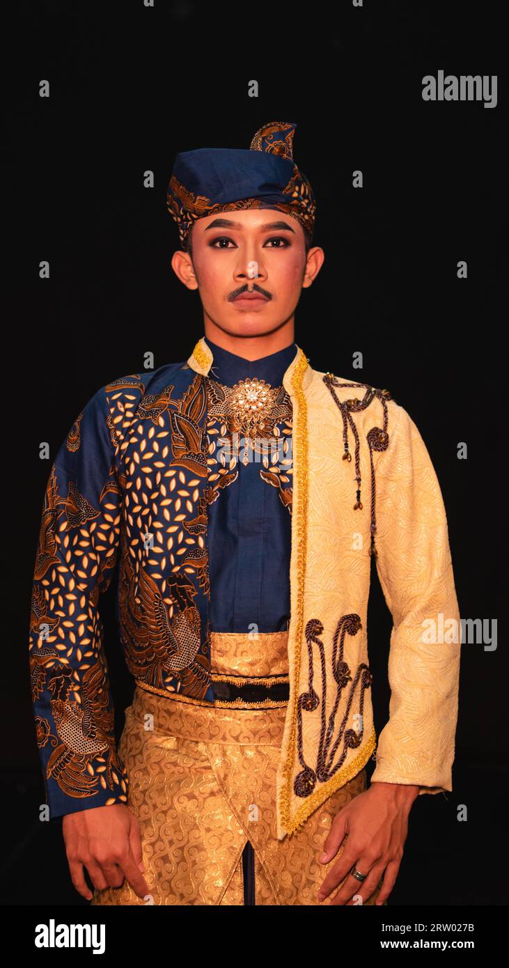 an Asian man wearing a traditional Indonesian dance costume is brown ...