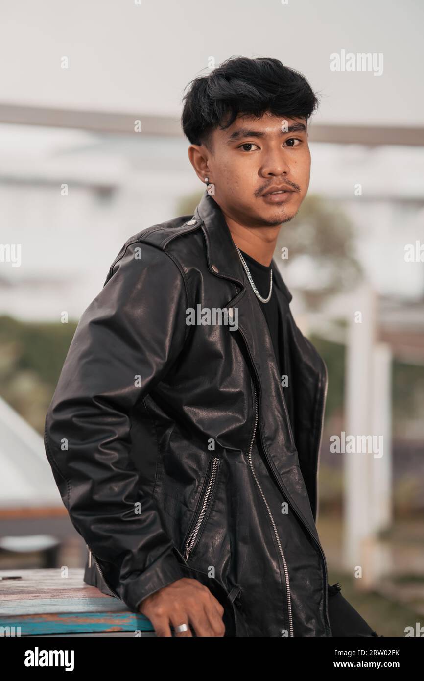 a grown man in a black leather suit and chain necklace posing very ...