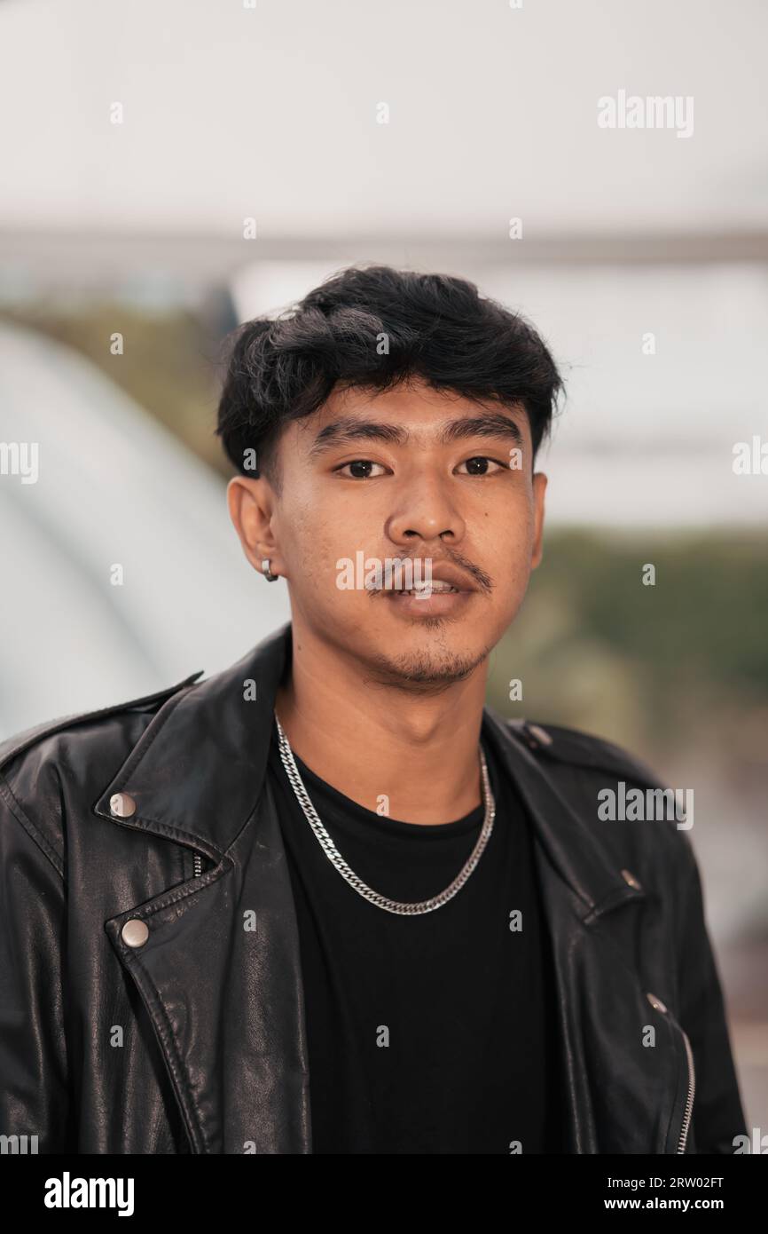 a grown man in a black leather suit and chain necklace posing very ...