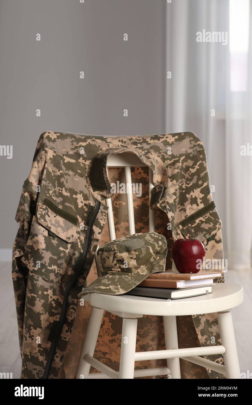 Chair with soldier uniform, notebooks and apple indoors. Military ...