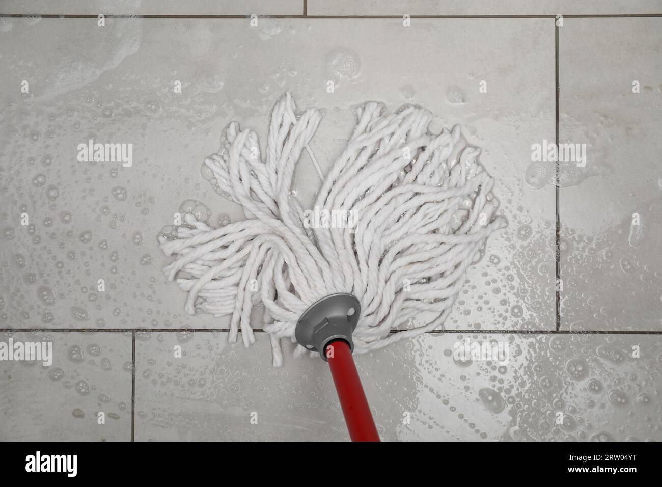 Cleaning grey tiled floor with string mop, top view Stock Photo - Alamy
