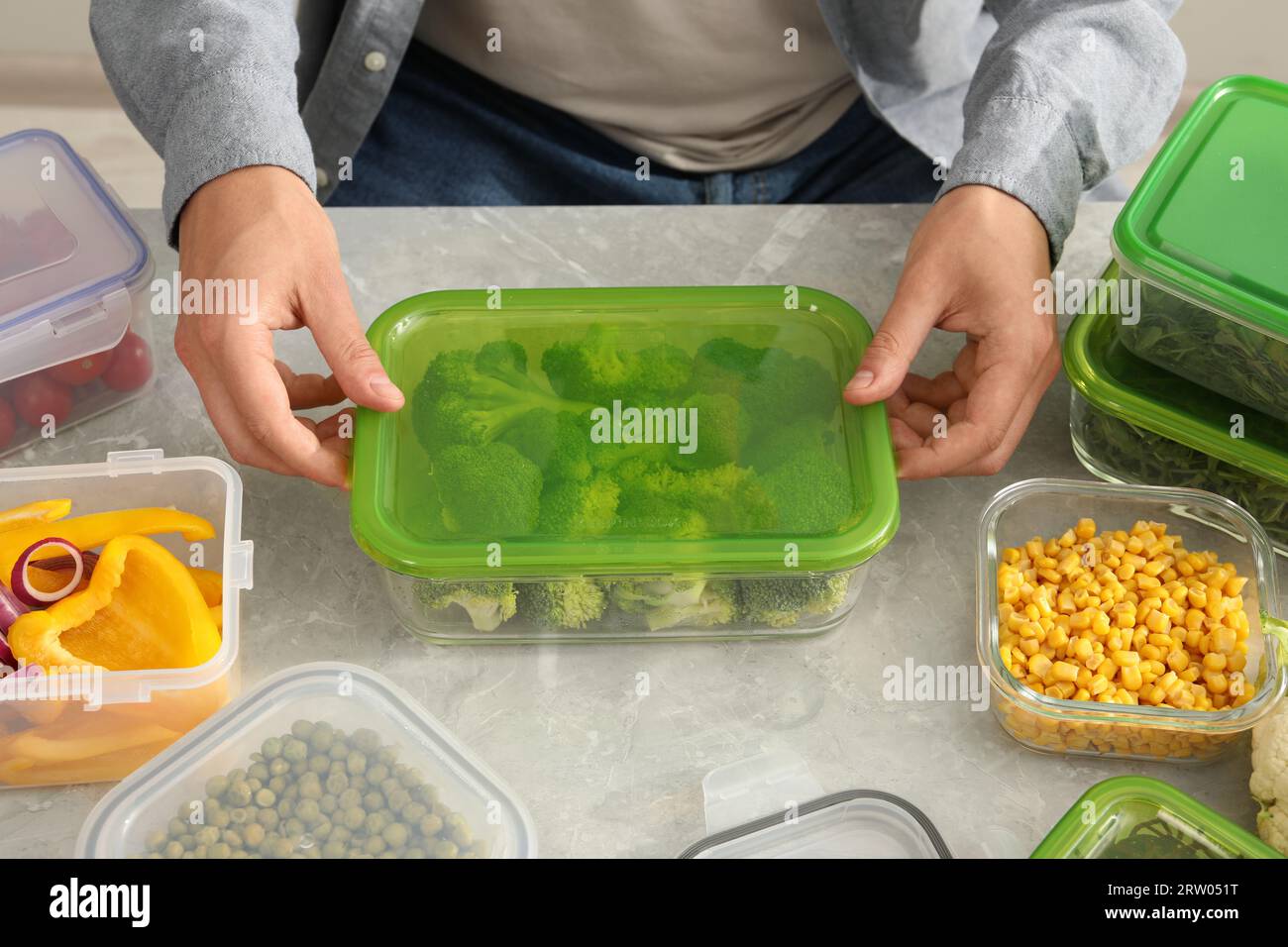 Man closing glass container with lid at light grey marble table in ...