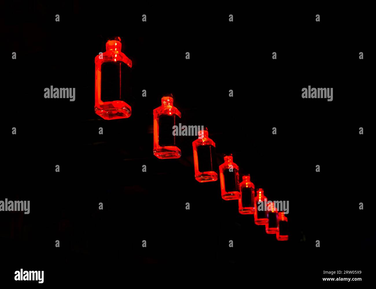 Red bottles with neon light element interior on a black background ...