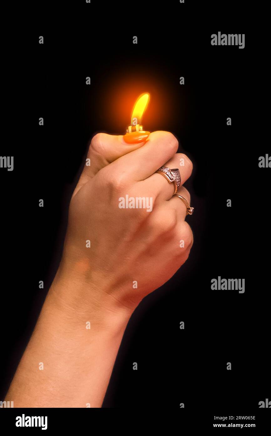 The girl's hand lights the bright fire of the lighter, the light in the ...