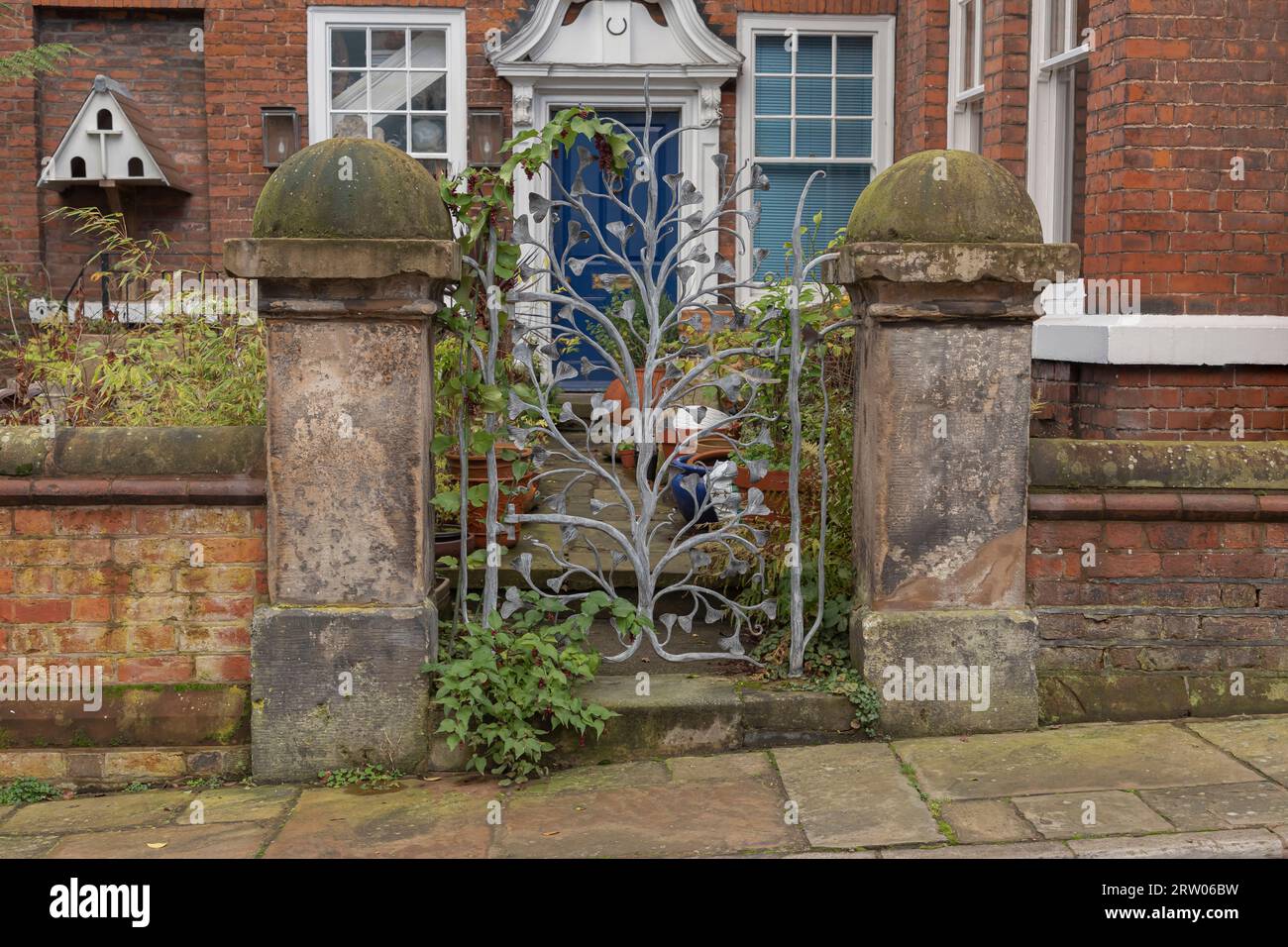Old sandstone gate posts with intricate iron gate which is closed and ...