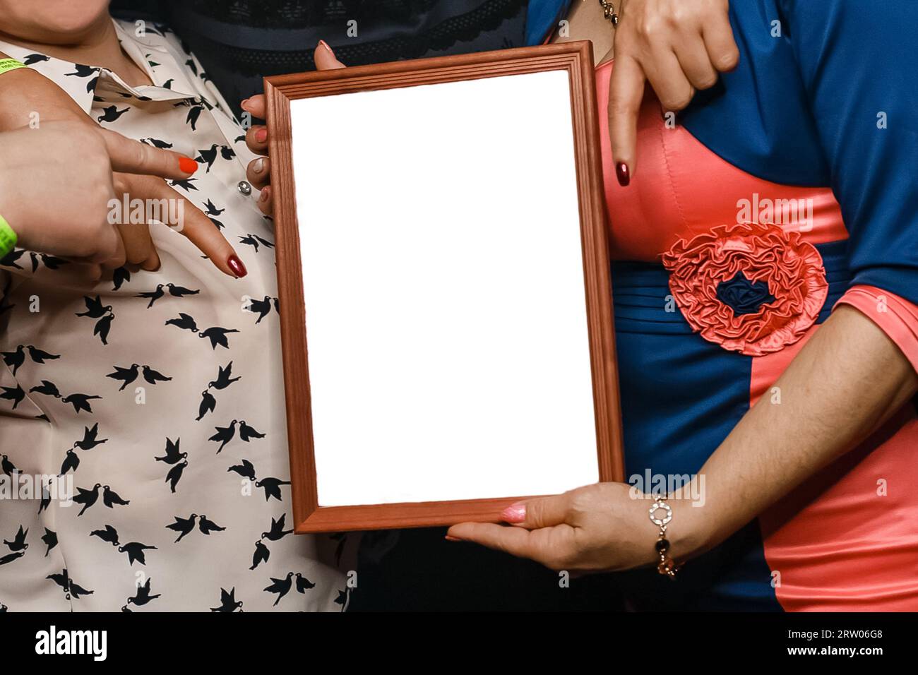 Adult women's hands point their finger at a blank white space frame ...