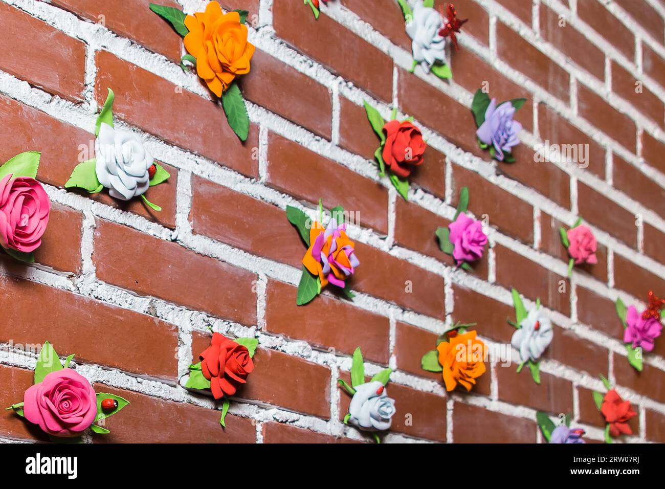 The brick wall is decorated with artificial objects, flowers, multi ...